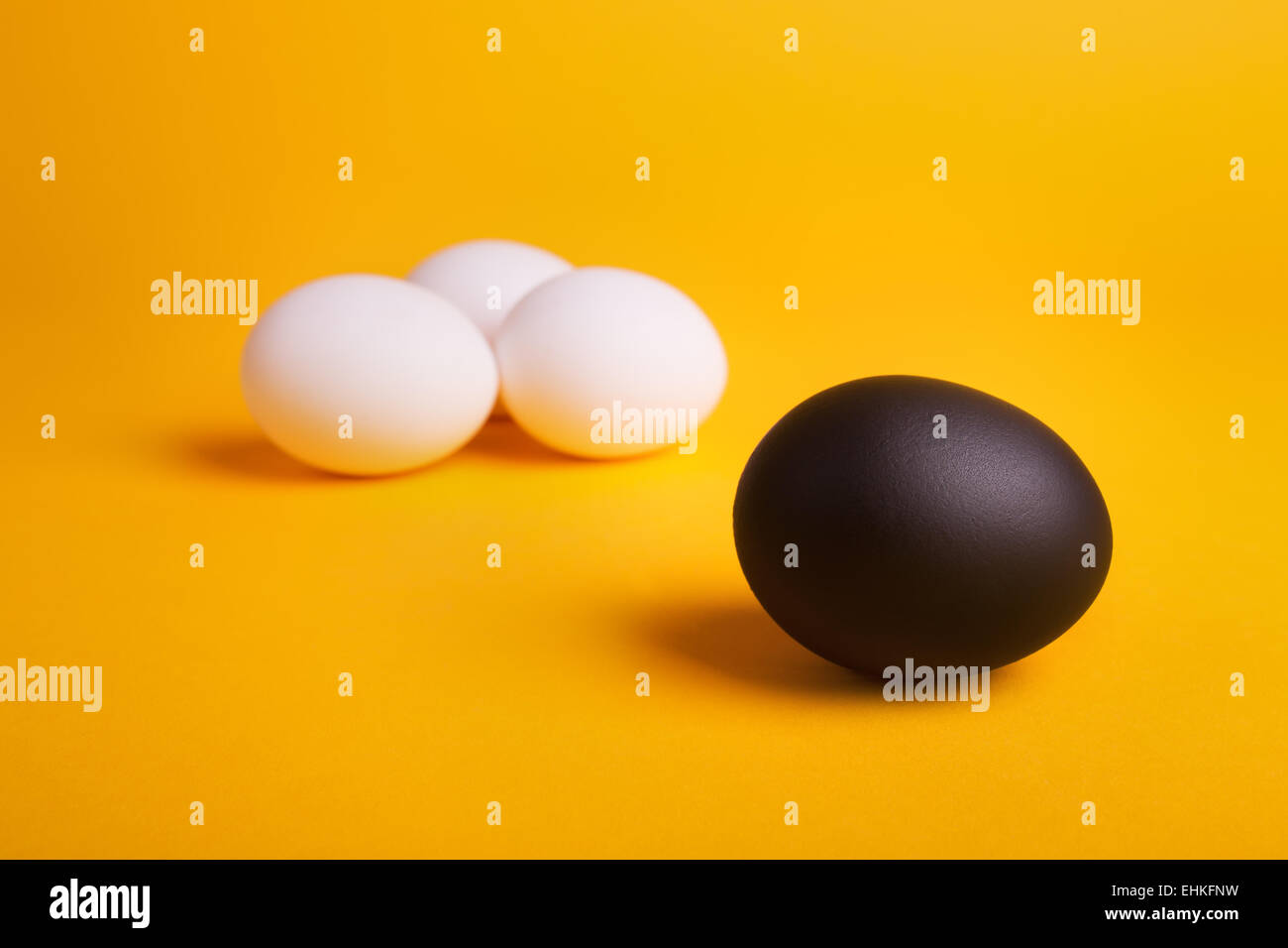 business concept background with a black egg surrounded by normal eggs ...