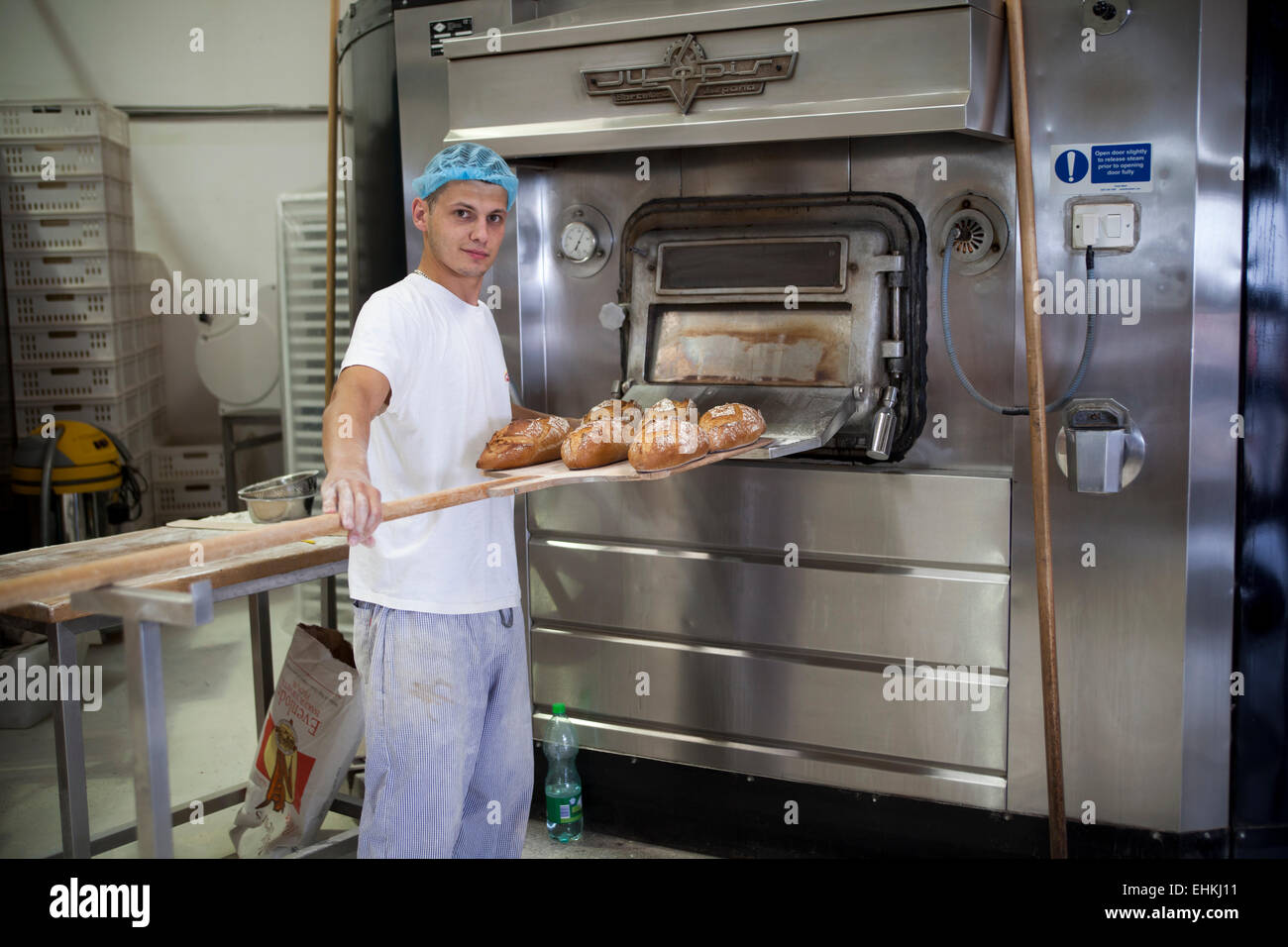 Baker placing loaves of bread in the oven Stock Photo - Alamy