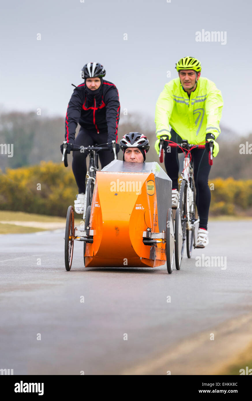 Two cyclists following behind a four wheeled recumbent cycle and rider ...