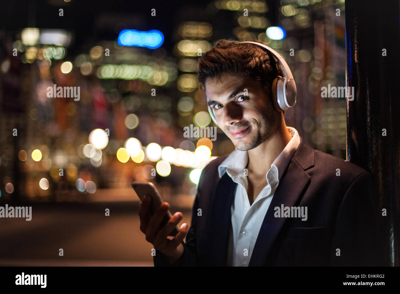 A young man listening to music or talking on his smartphone in the city ...