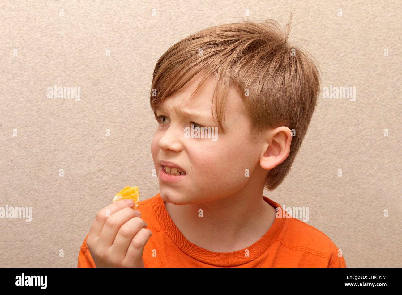 boy eating acid piece of orange Stock Photo - Alamy