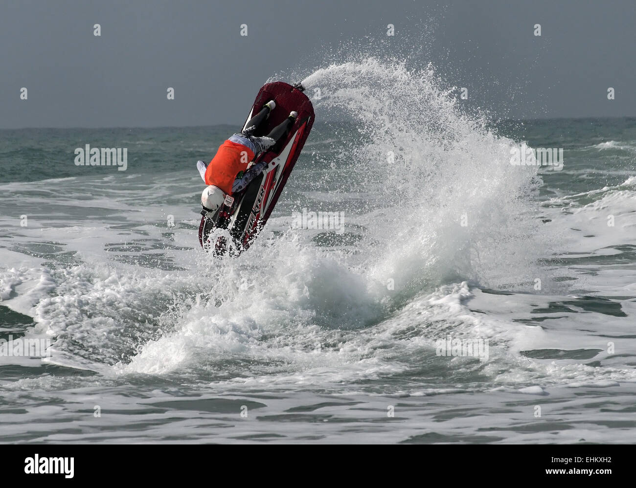 Male jet ski competitor performs aerial action moves in large breaking ...