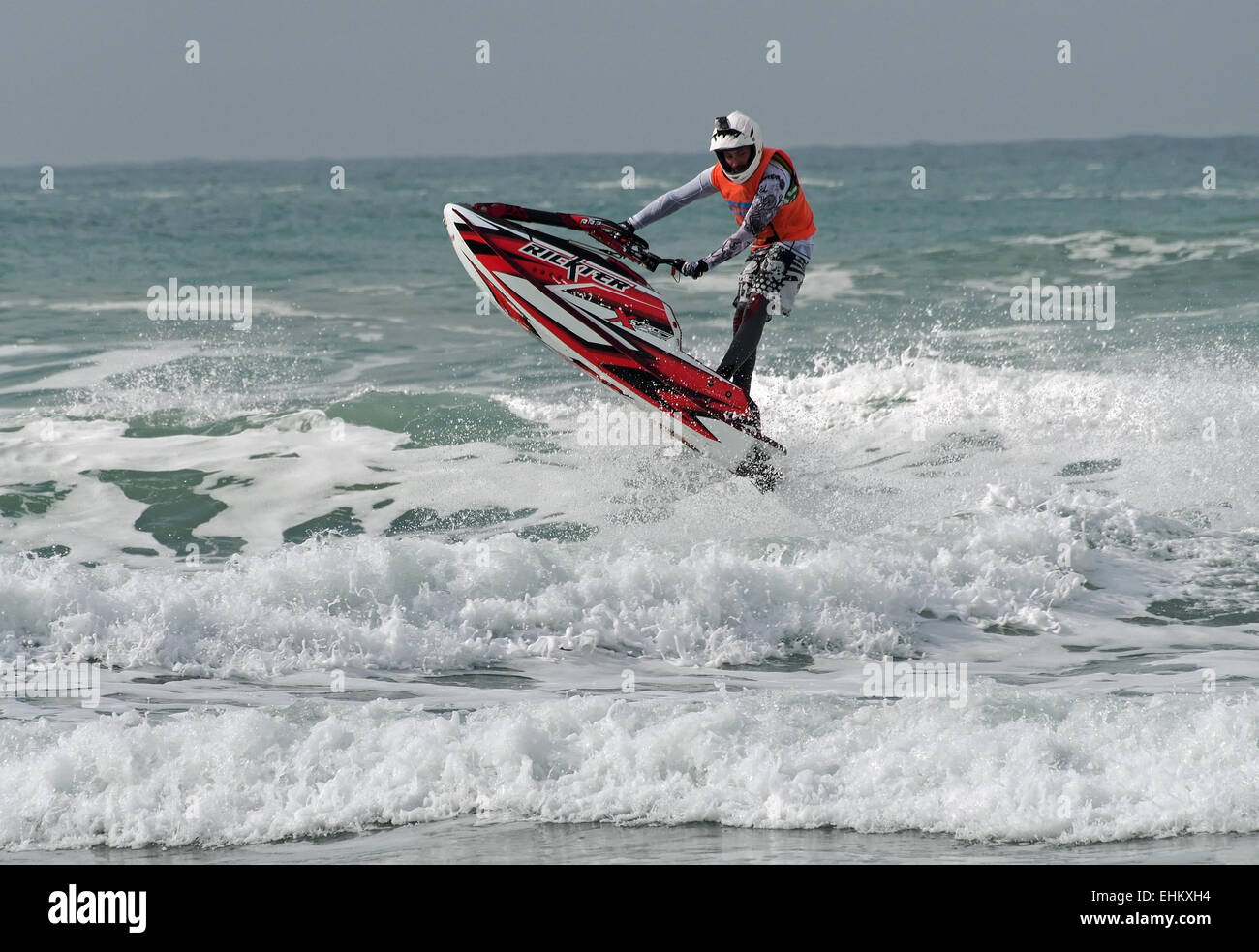 Male jet ski competitor performs aerial action moves in large breaking ...