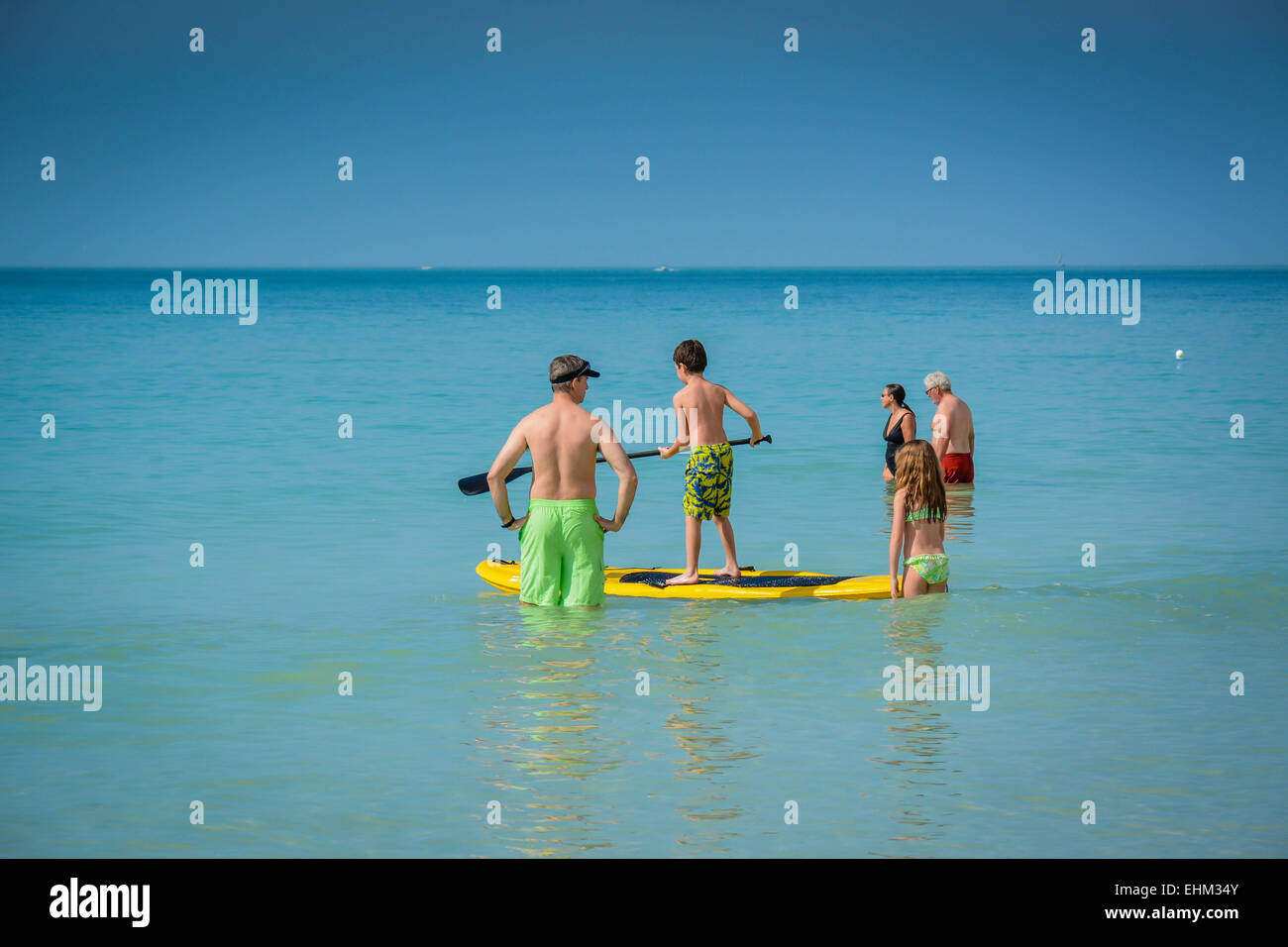 Father oversees son's attempt at paddle boarding in the shallow and ...