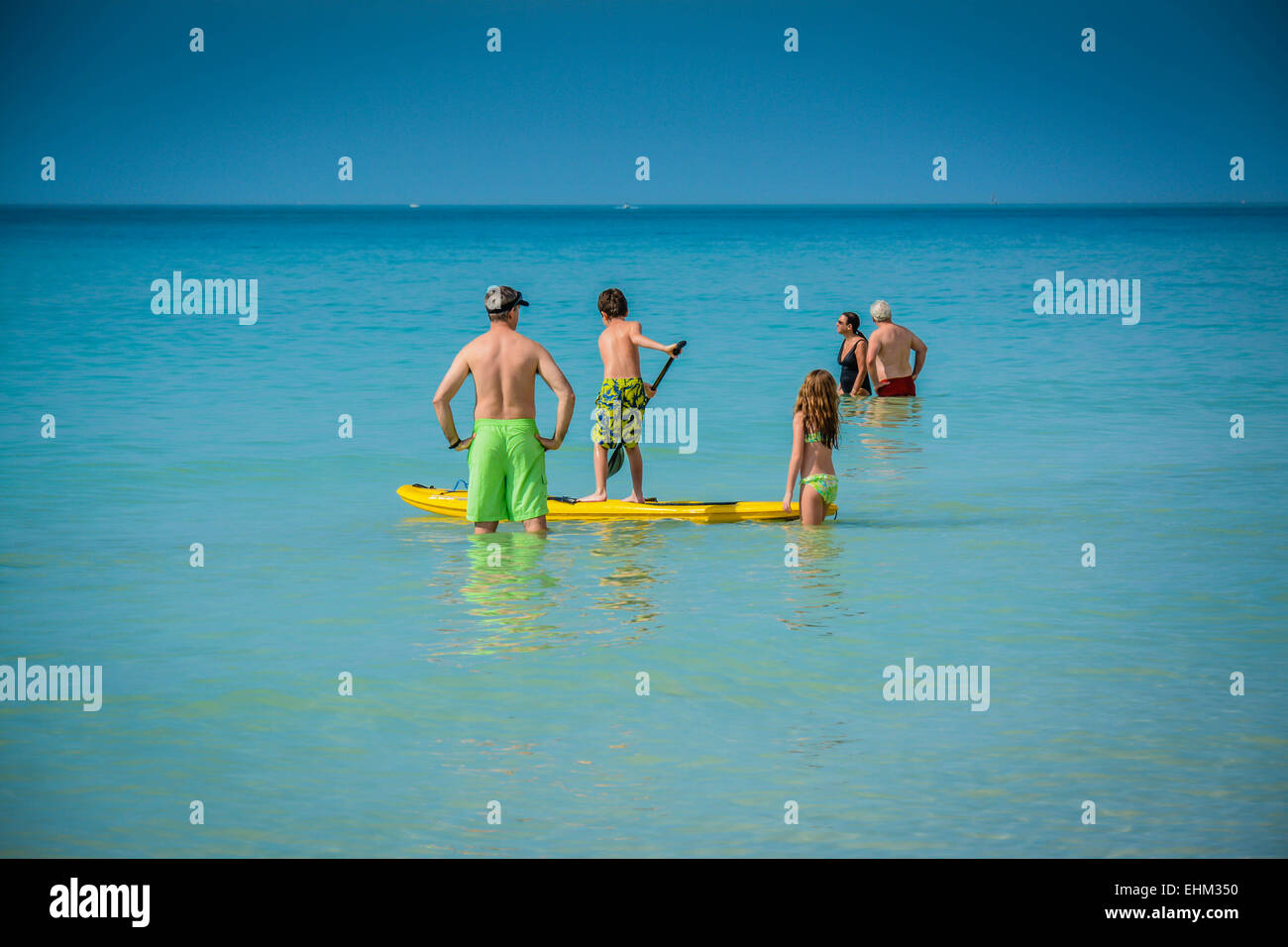 Father oversees son's attempt at paddle boarding in the shallow and ...
