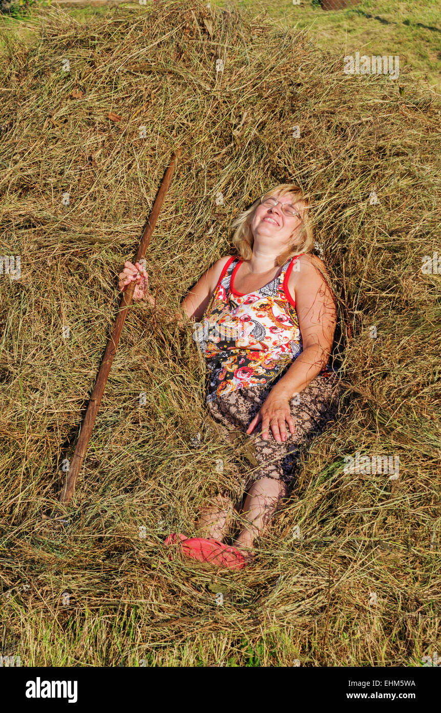 The happy woman gathering a hay pile in the village Stock Photo - Alamy