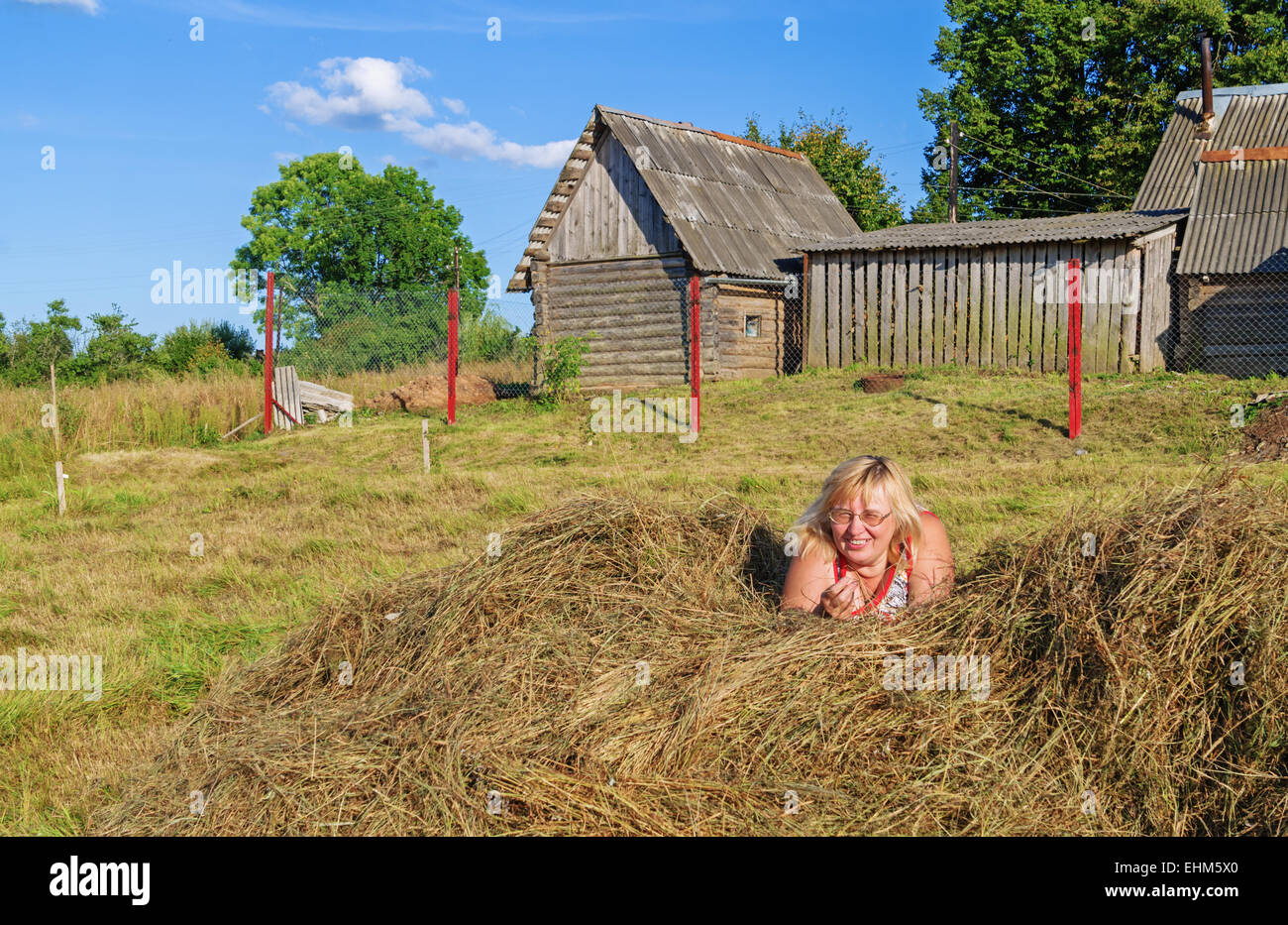 The happy woman gathering a hay pile in the village Stock Photo - Alamy