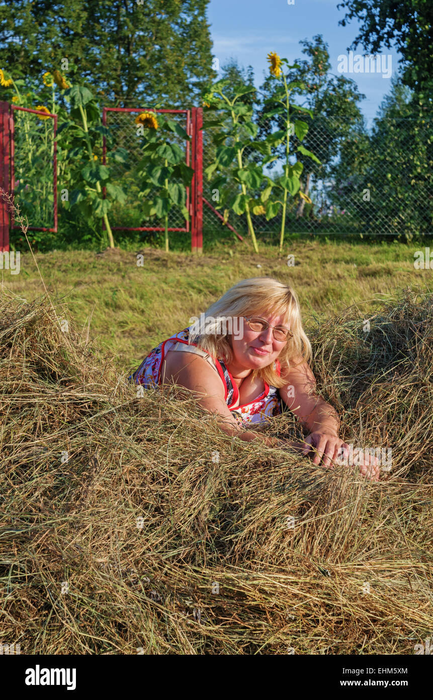 The happy woman gathering a hay pile in the village Stock Photo - Alamy