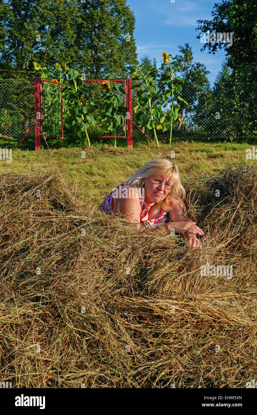 The happy woman gathering a hay pile in the village Stock Photo - Alamy