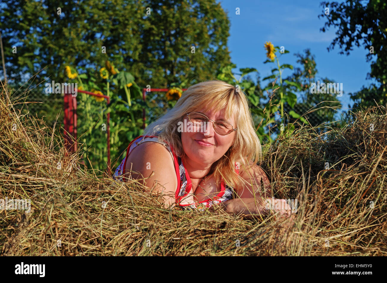 The happy woman gathering a hay pile in the village Stock Photo - Alamy