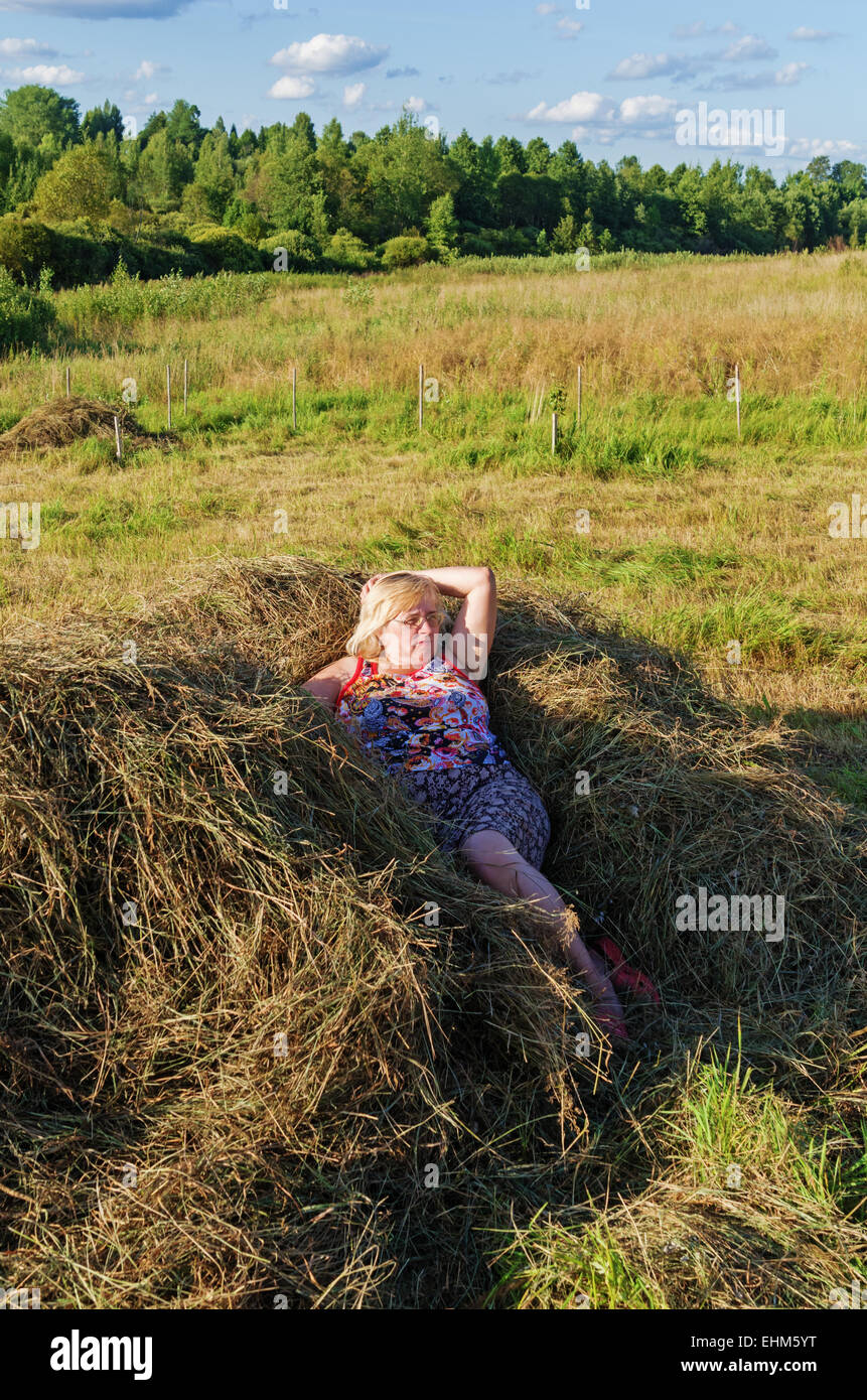 The happy woman gathering a hay pile in the village Stock Photo - Alamy