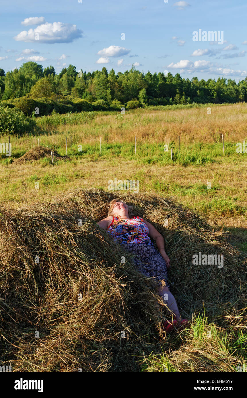 The happy woman gathering a hay pile in the village Stock Photo - Alamy