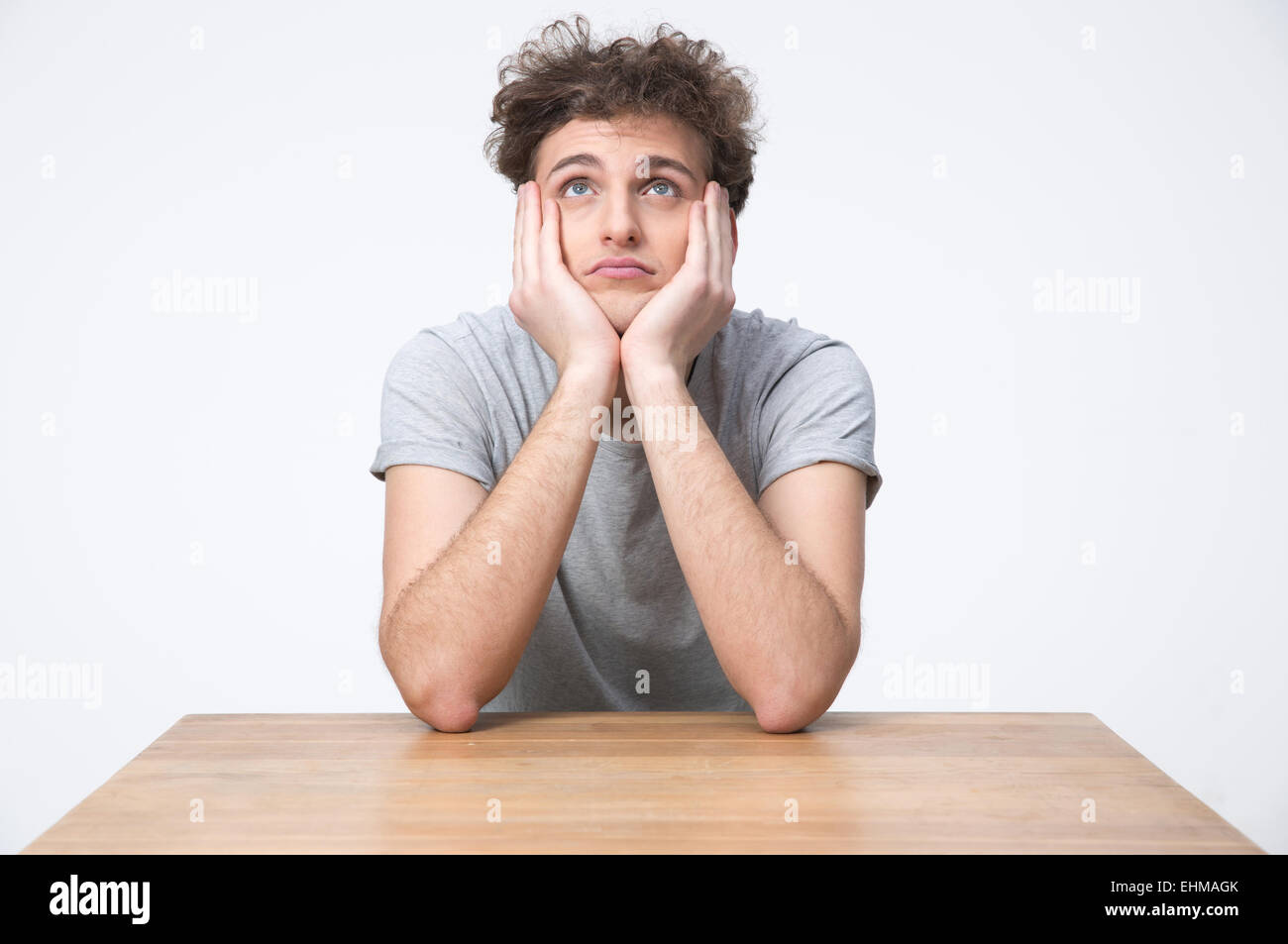 Handsome young man sitting at the table and looking up Stock Photo - Alamy