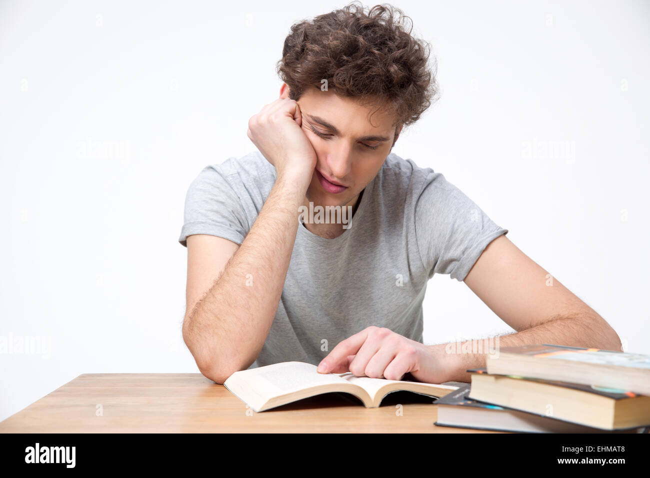 Tired male student sitting at the table with books Stock Photo - Alamy