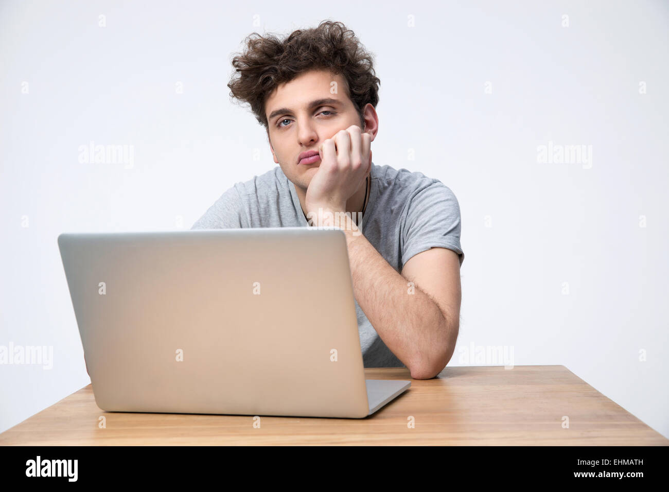 Tired man sitting at the table with laptop over gray background Stock ...