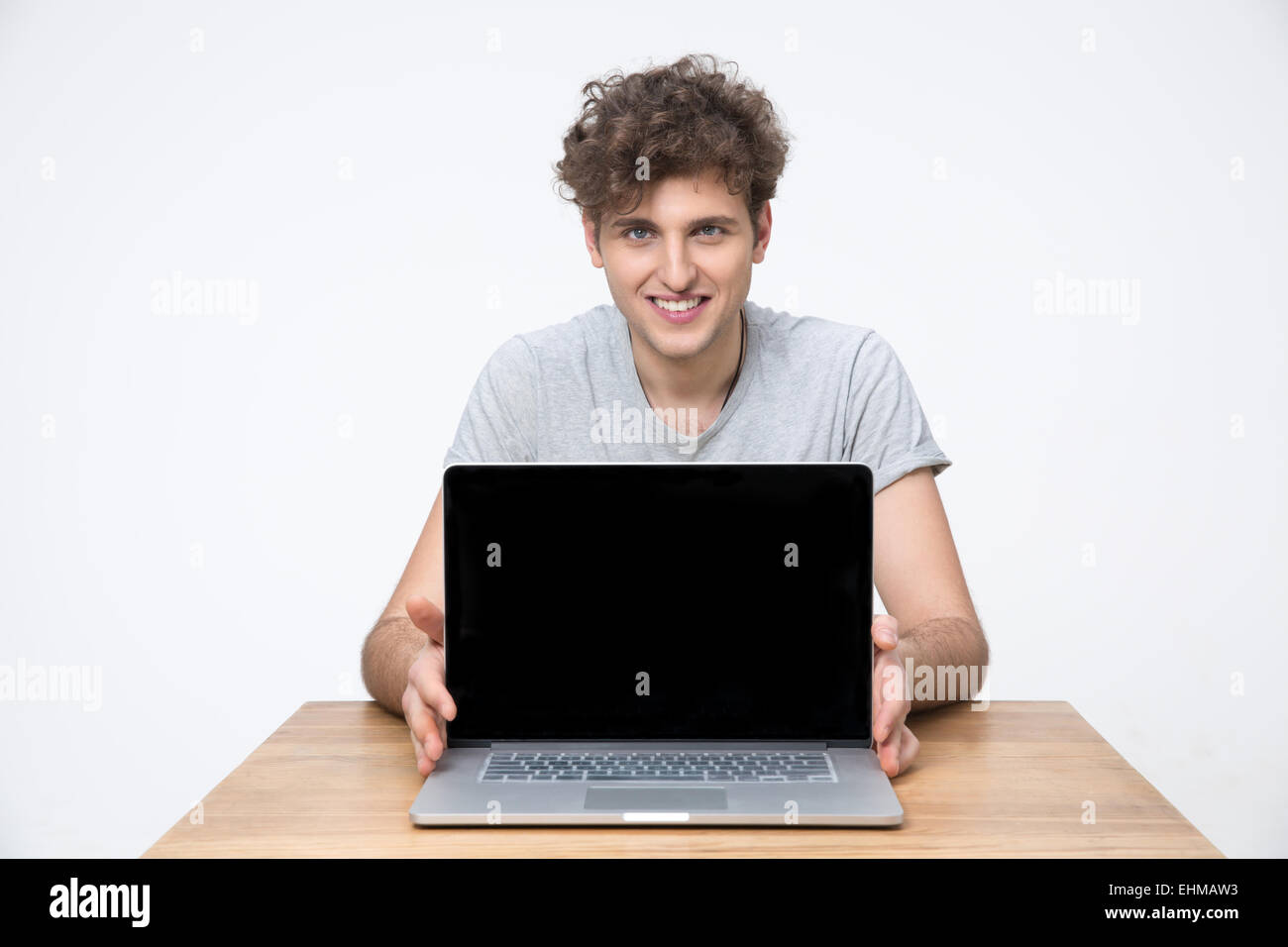 Cheerful man sitting at the table and showing laptop screen Stock Photo ...