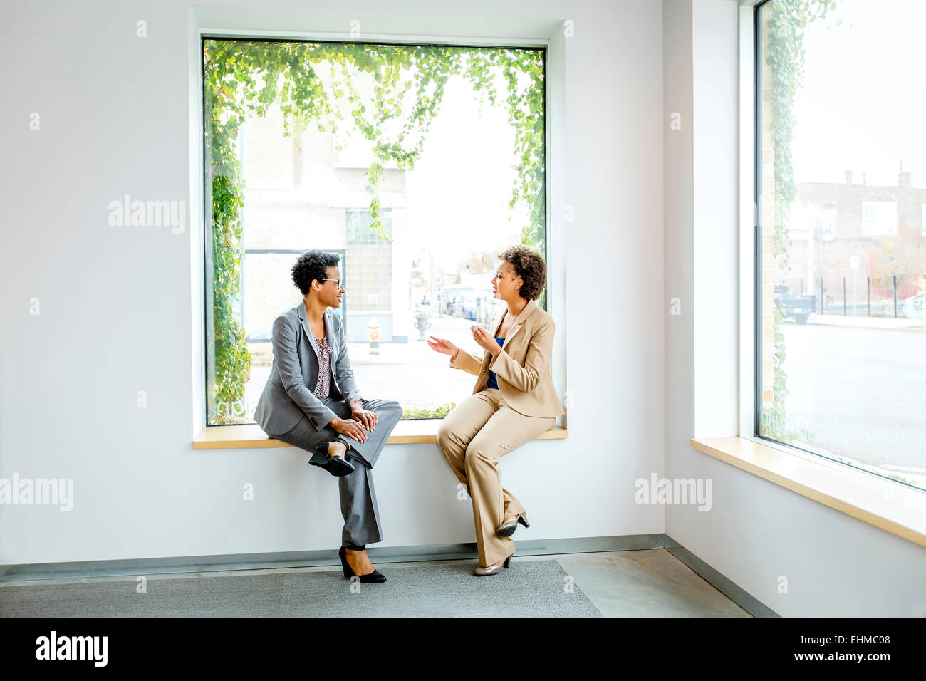 Businesswomen talking in window of office lobby Stock Photo - Alamy