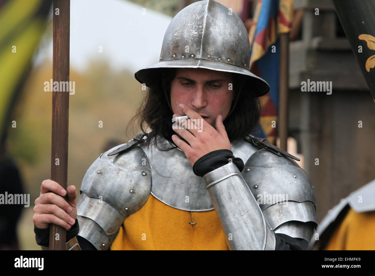 Background actor Adam Průcha dressed as a medieval guard smokes a ...