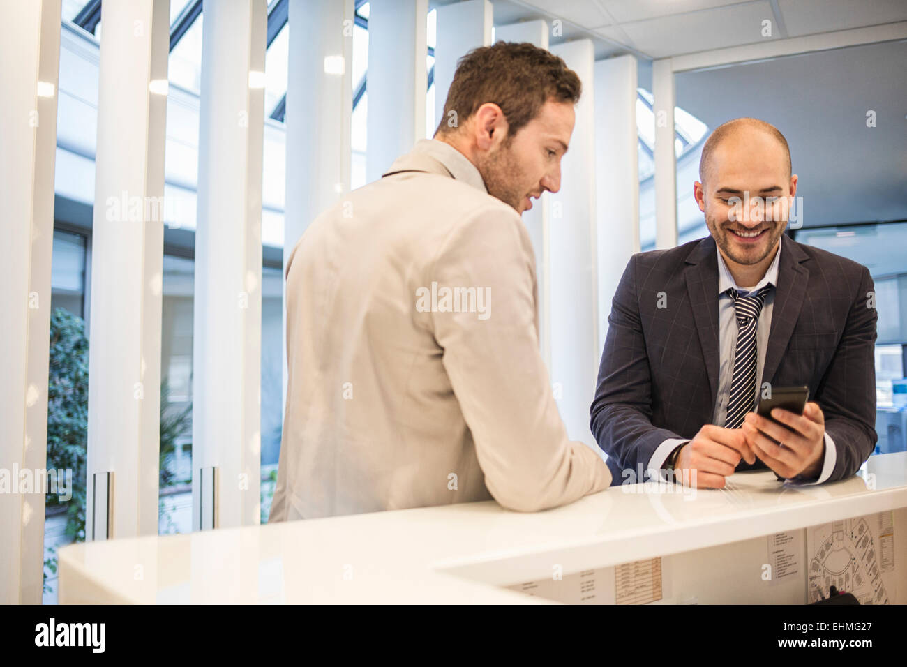 Caucasian businessmen using cell phone in office lobby Stock Photo - Alamy