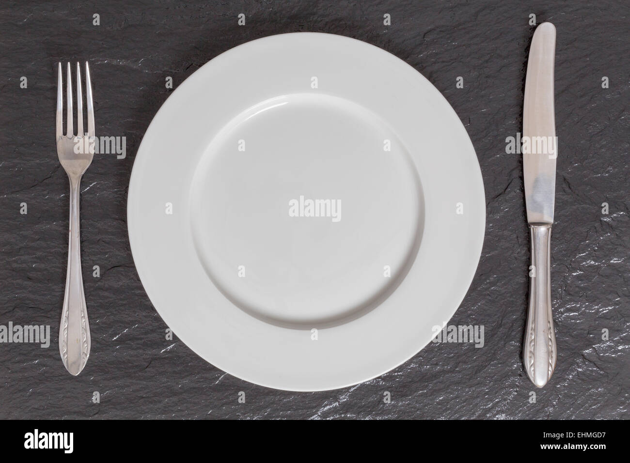 Empty plate with utensils on slate in bird's eye view Stock Photo - Alamy