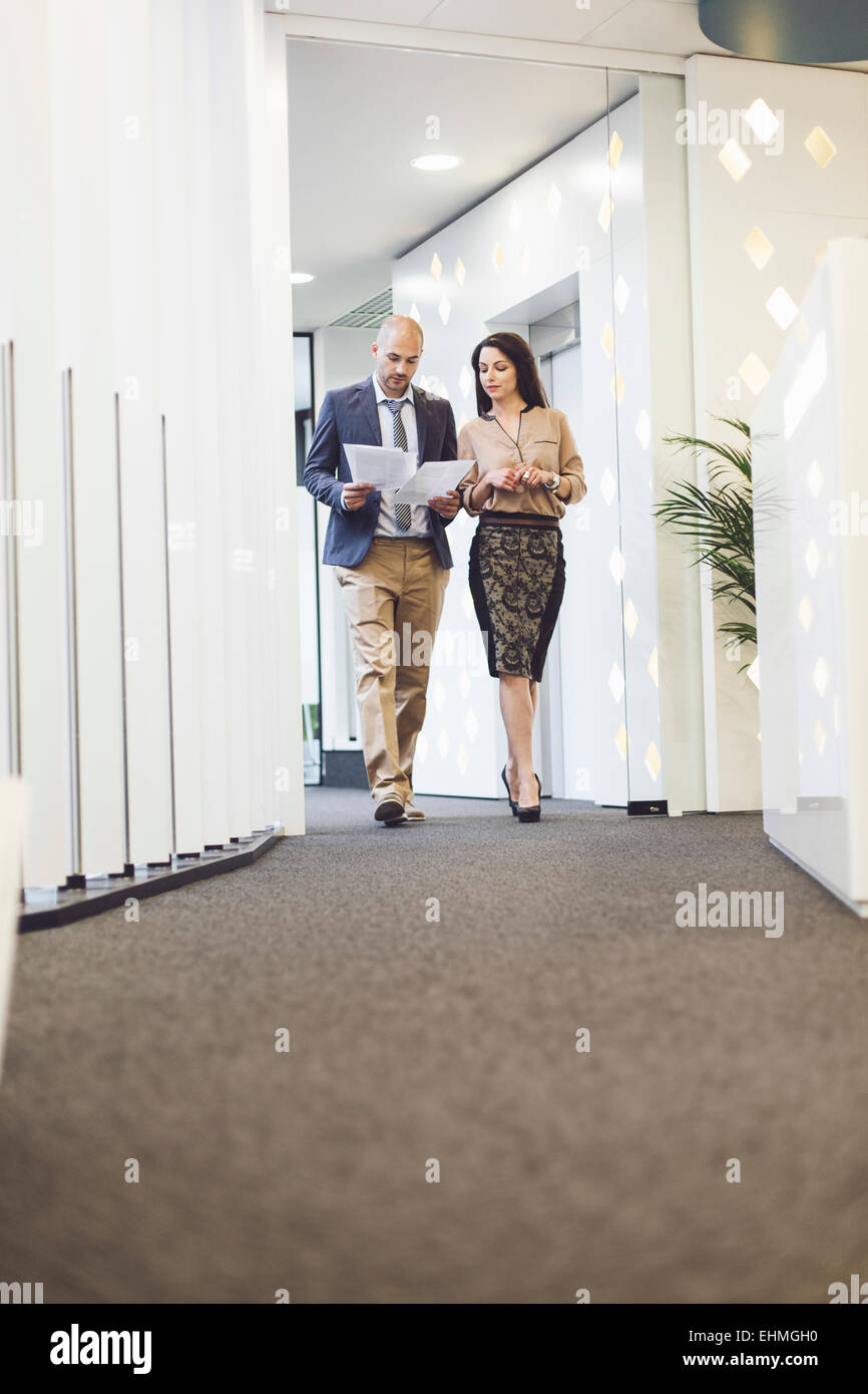 Caucasian business people reading paperwork in office corridor Stock ...