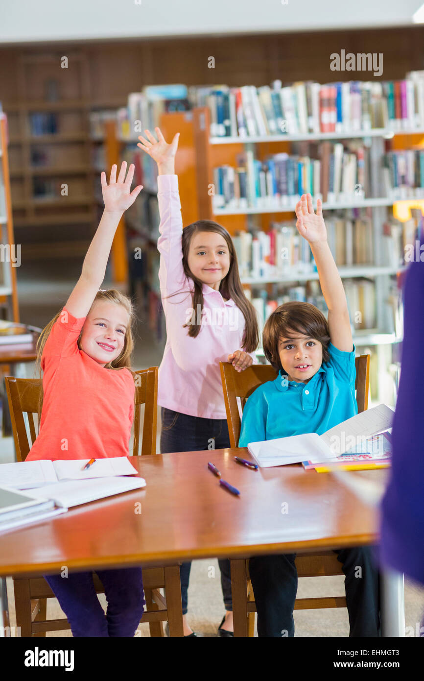 Students raising their hands in library Stock Photo - Alamy