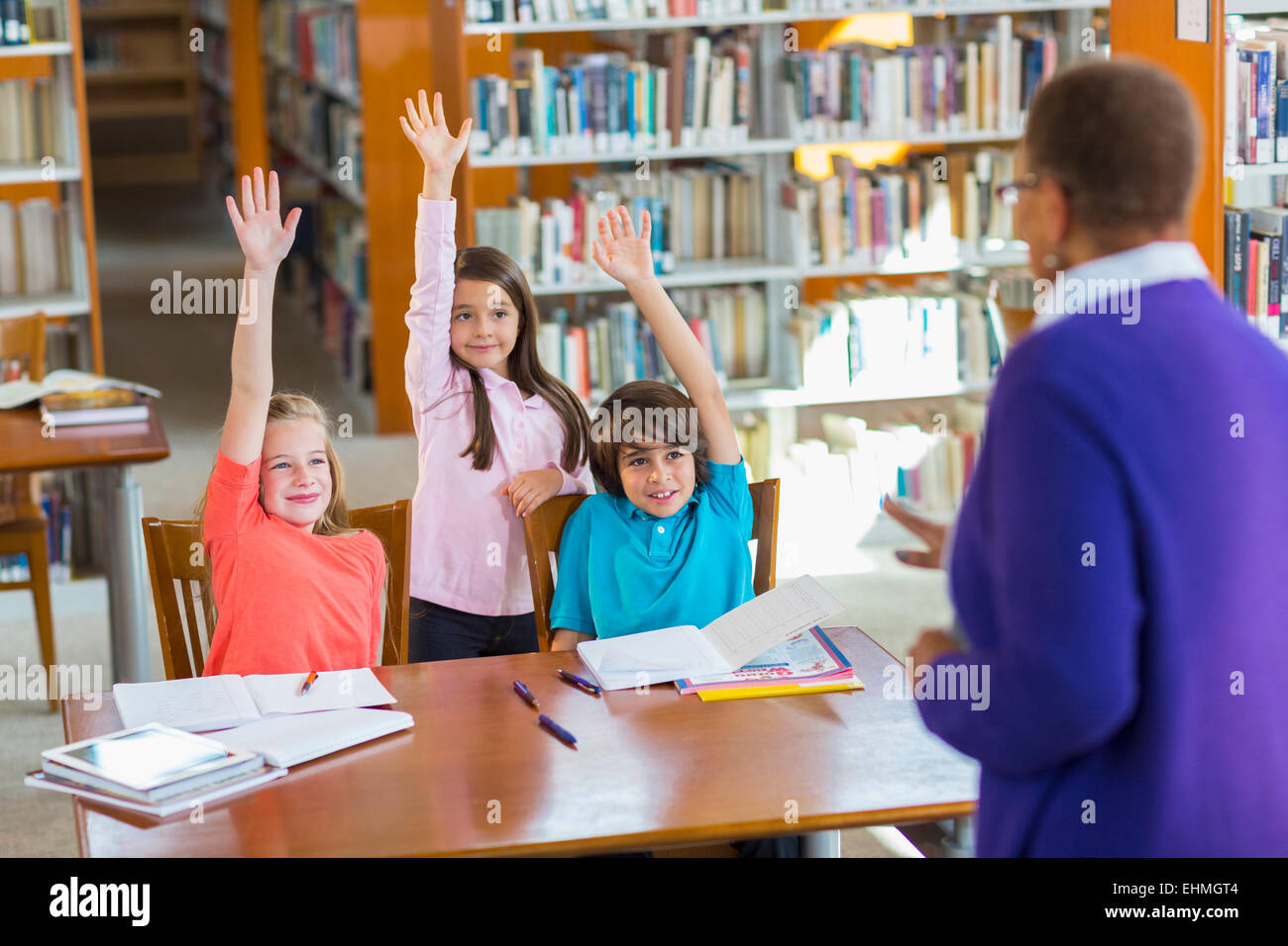 Students raising their hands in library Stock Photo - Alamy