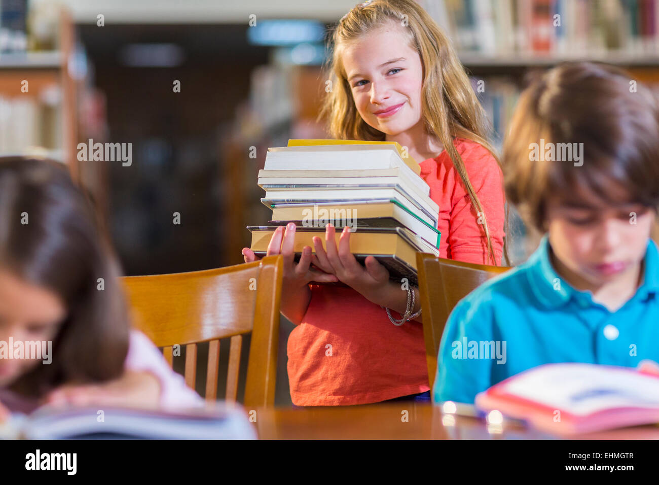 Student carrying stack of books in library Stock Photo - Alamy