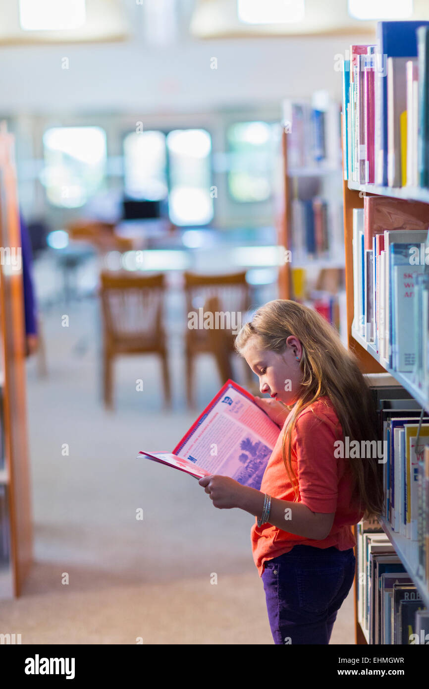 Caucasian student reading book in library Stock Photo - Alamy