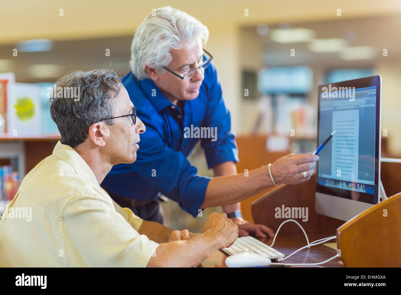 Teacher helping adult student use computer in library Stock Photo - Alamy