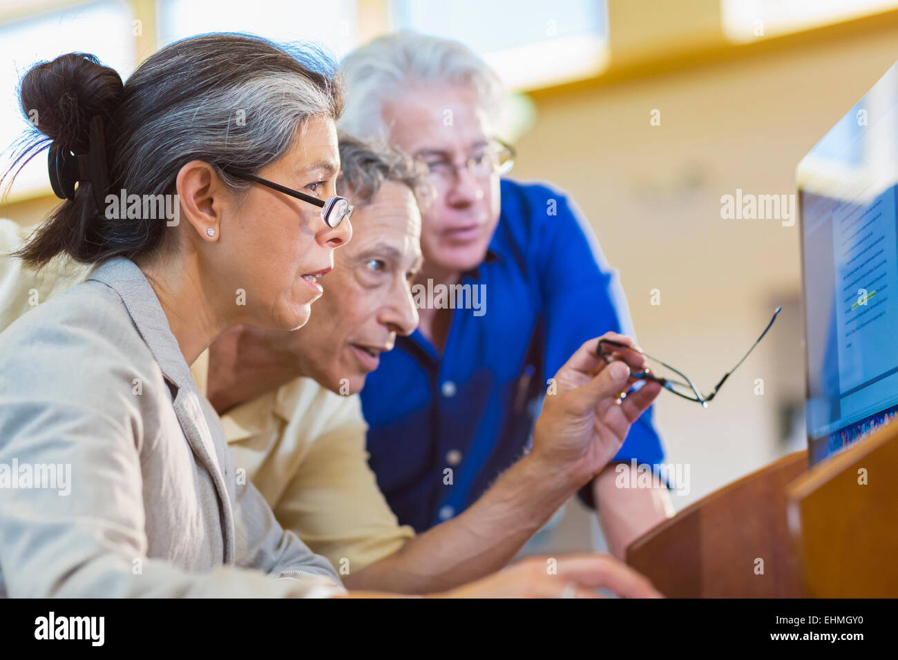Teacher helping adult students use computer in library Stock Photo - Alamy