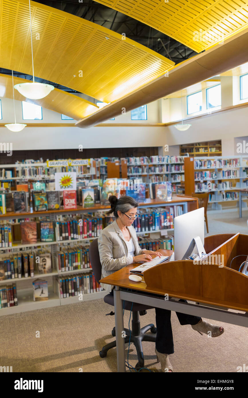 Hispanic woman using computer in library Stock Photo - Alamy
