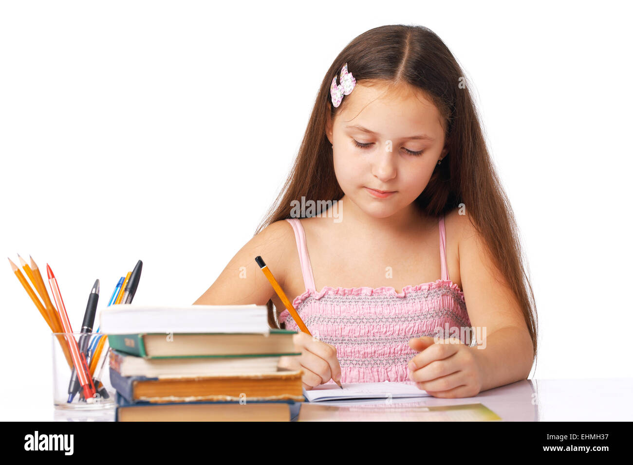 Cute little girl writing something in the copybook with pencils and ...