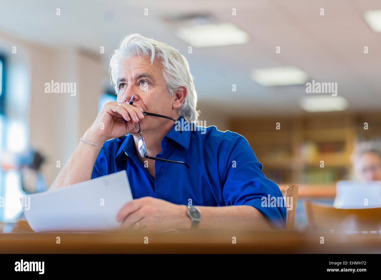 Man reading paperwork in library Stock Photo - Alamy
