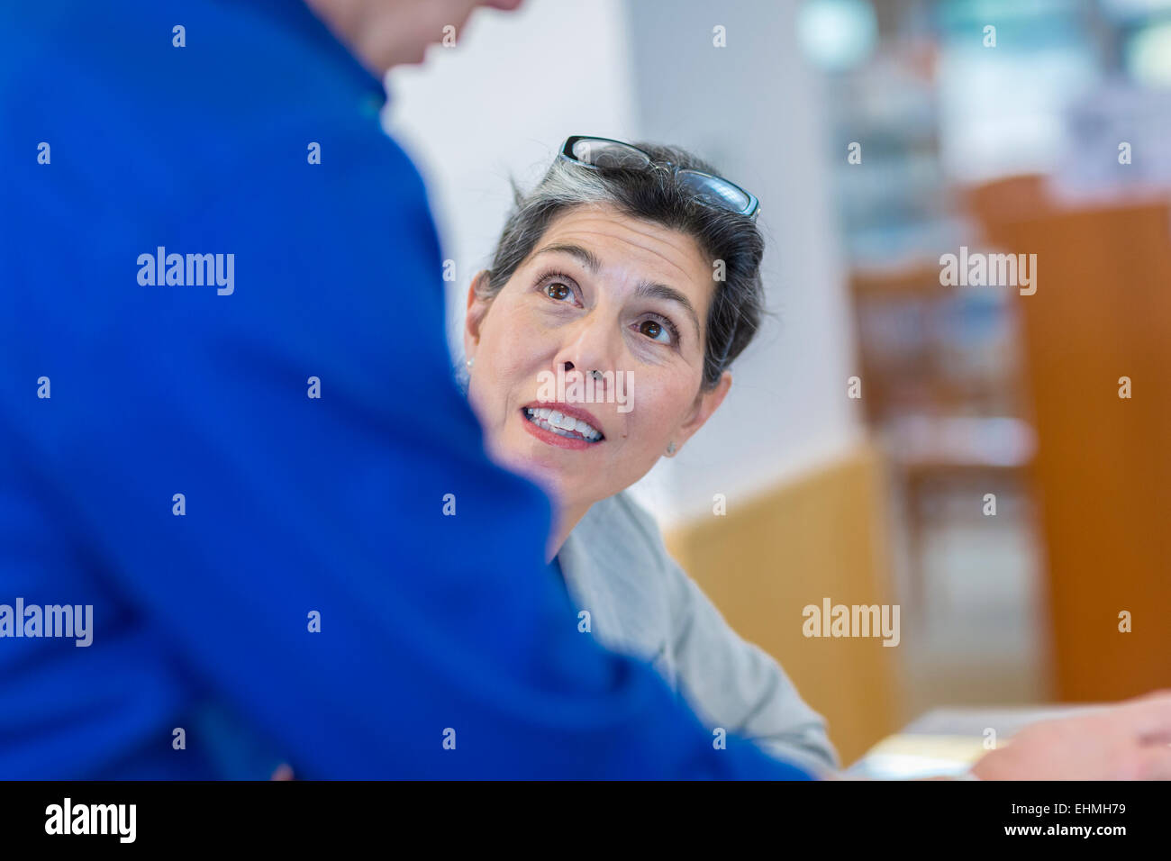 Hispanic teacher helping adult student in library Stock Photo - Alamy