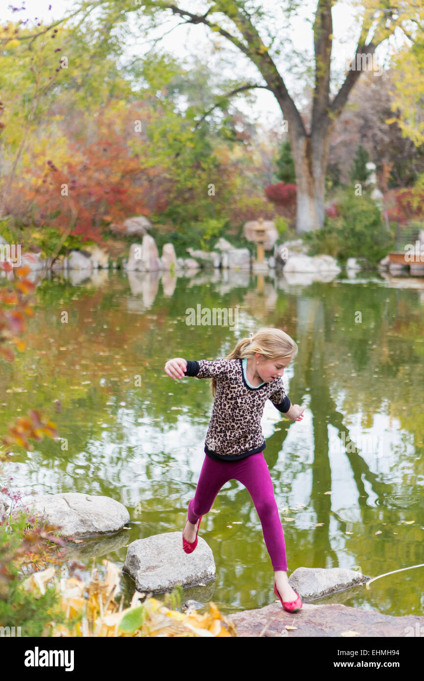 Caucasian girl jumping on rocks in pond Stock Photo - Alamy