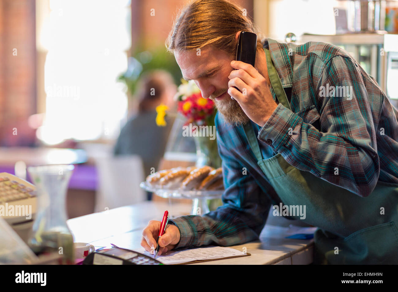 Caucasian server on telephone writing on clipboard Stock Photo - Alamy