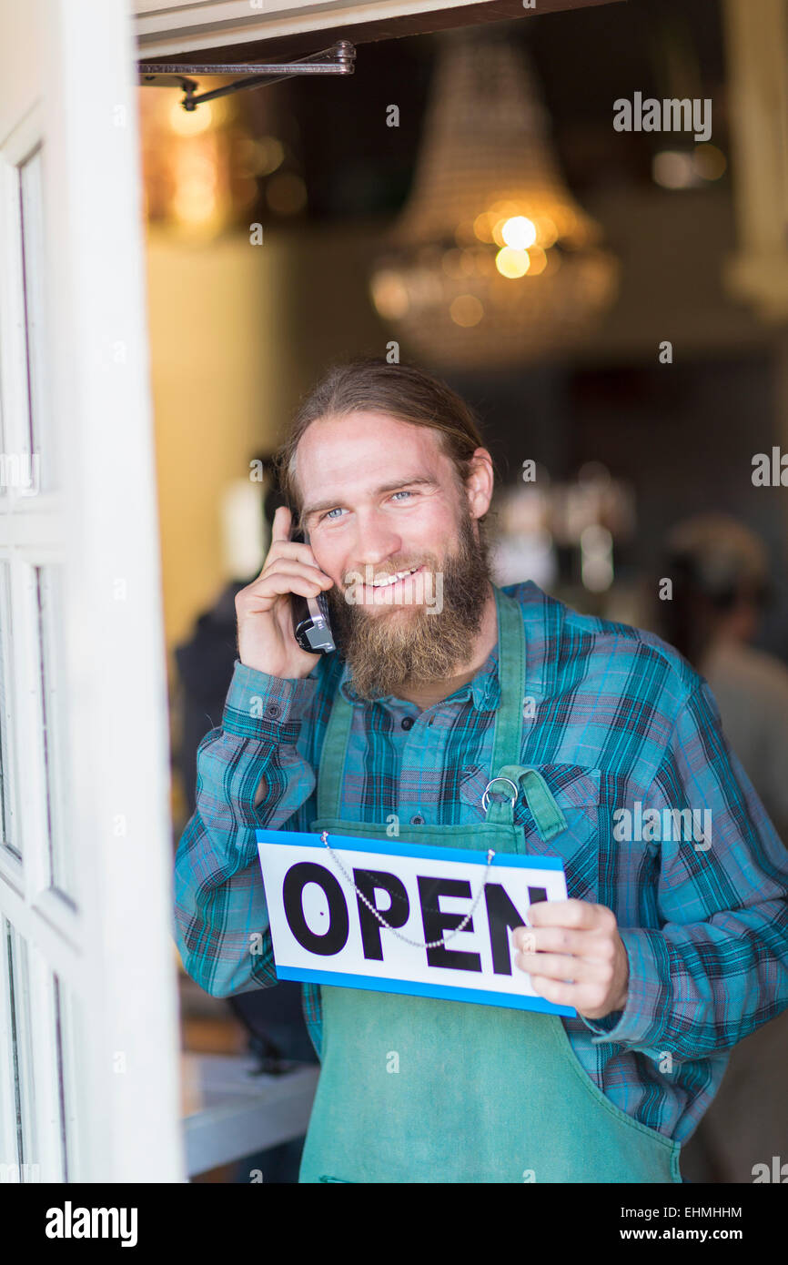 Caucasian server on telephone hanging open sign on cafe window Stock ...