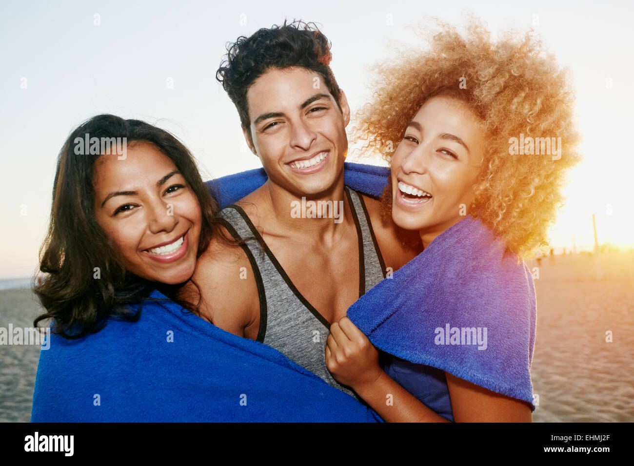 Hispanic friends wrapped in blanket on beach Stock Photo - Alamy