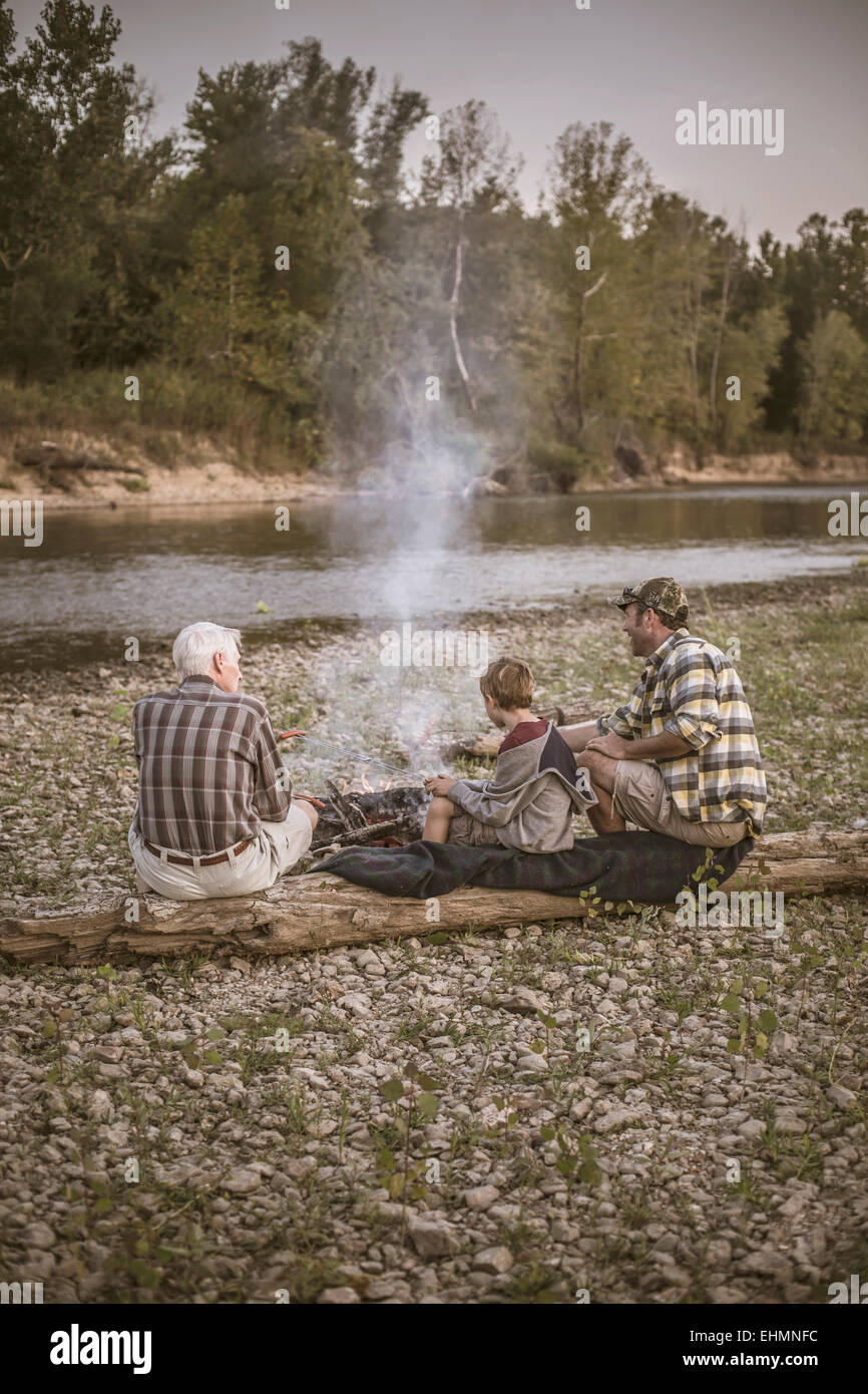 Three generations of Caucasian men relaxing near campfire Stock Photo ...