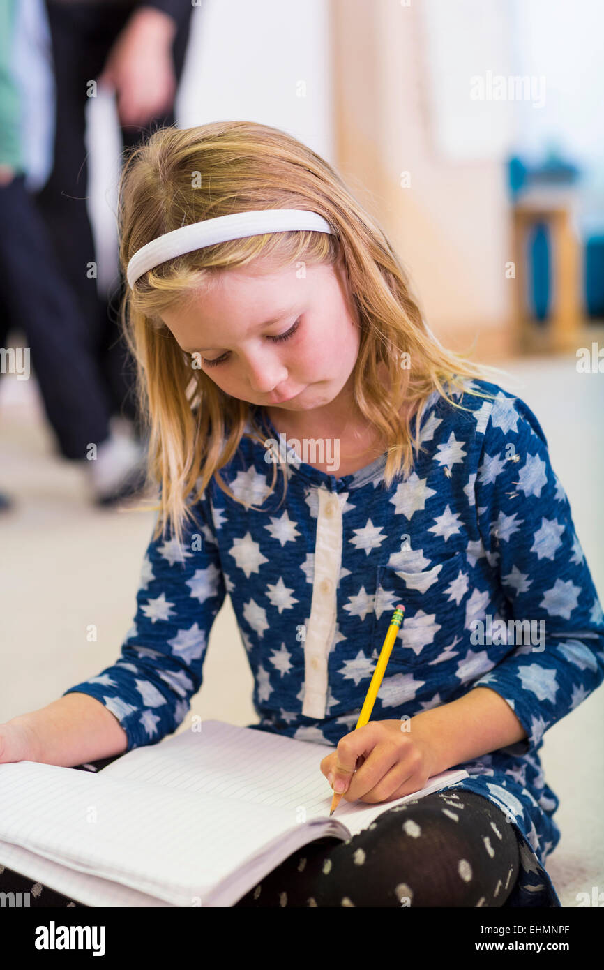 Caucasian girl writing in classroom Stock Photo - Alamy