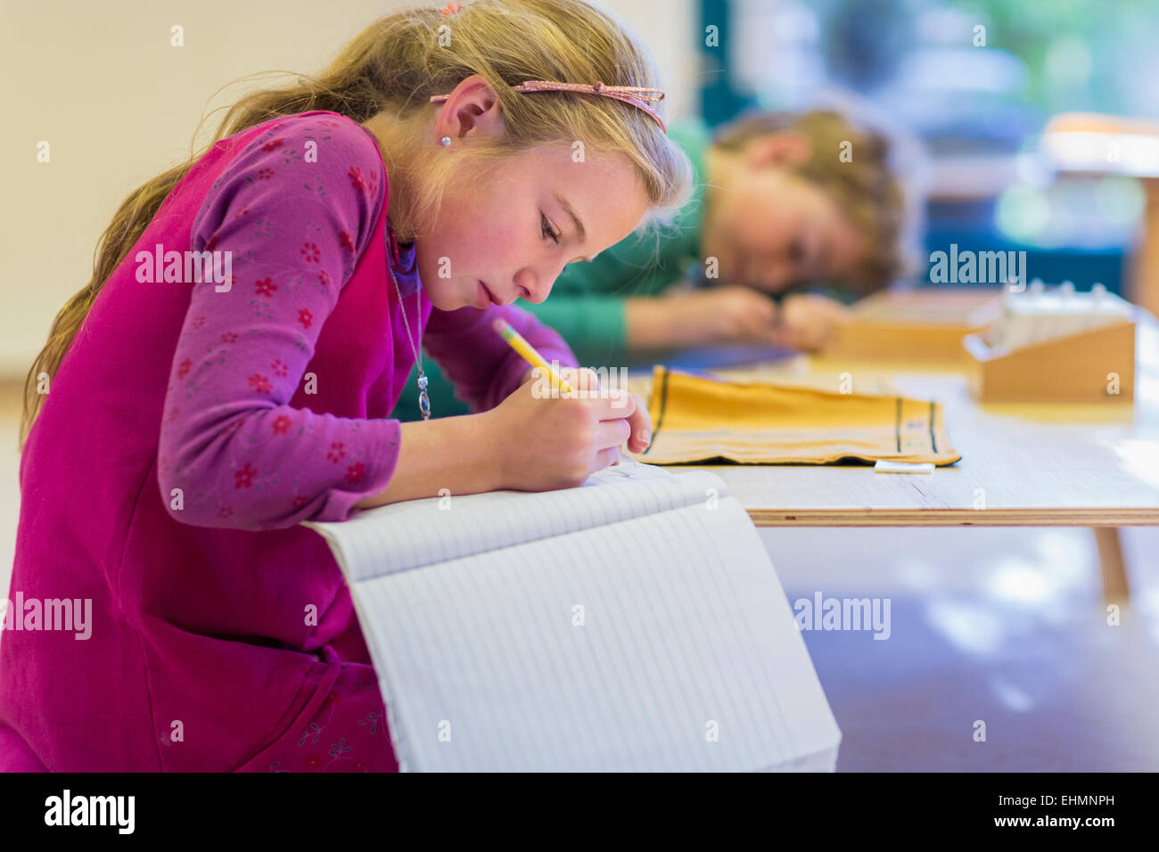 Caucasian girl writing in classroom Stock Photo - Alamy
