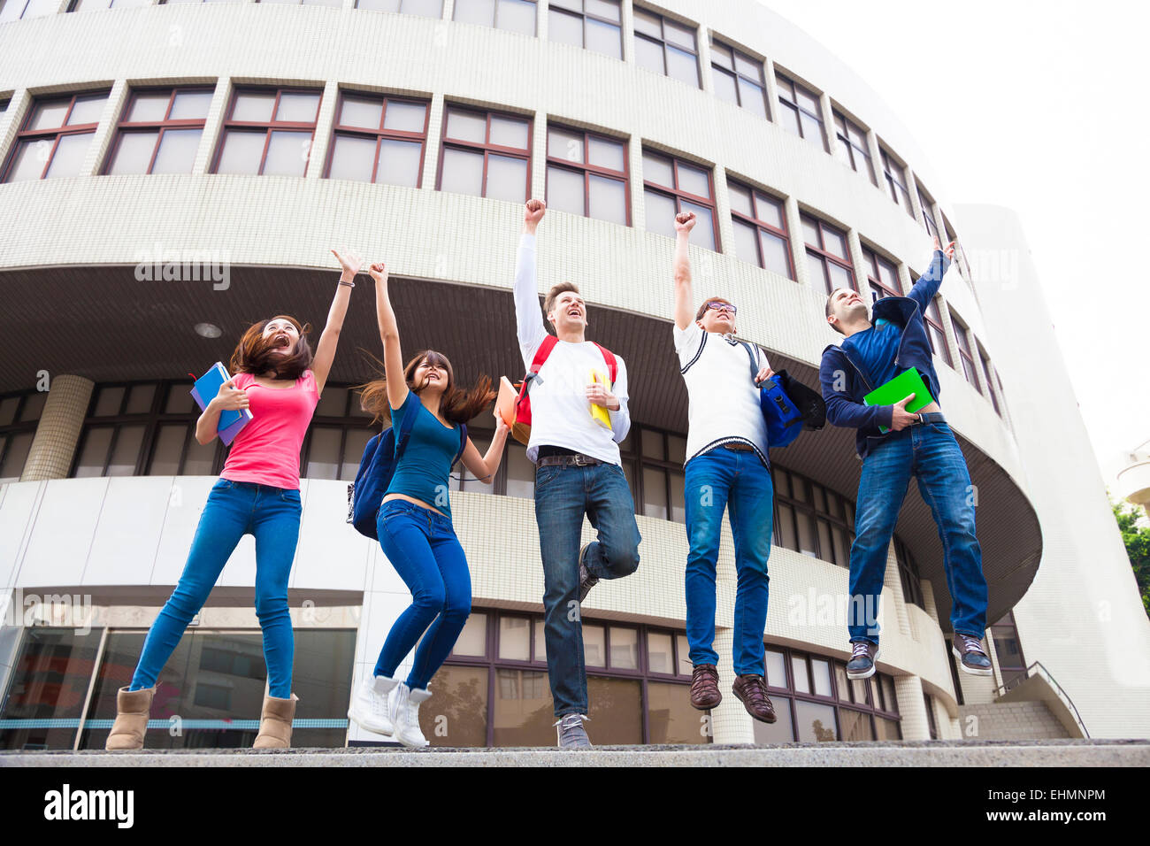 Happy young group of students jumping together Stock Photo - Alamy