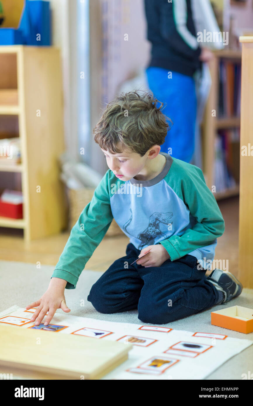 Boy arranging cards on floor in classroom Stock Photo - Alamy
