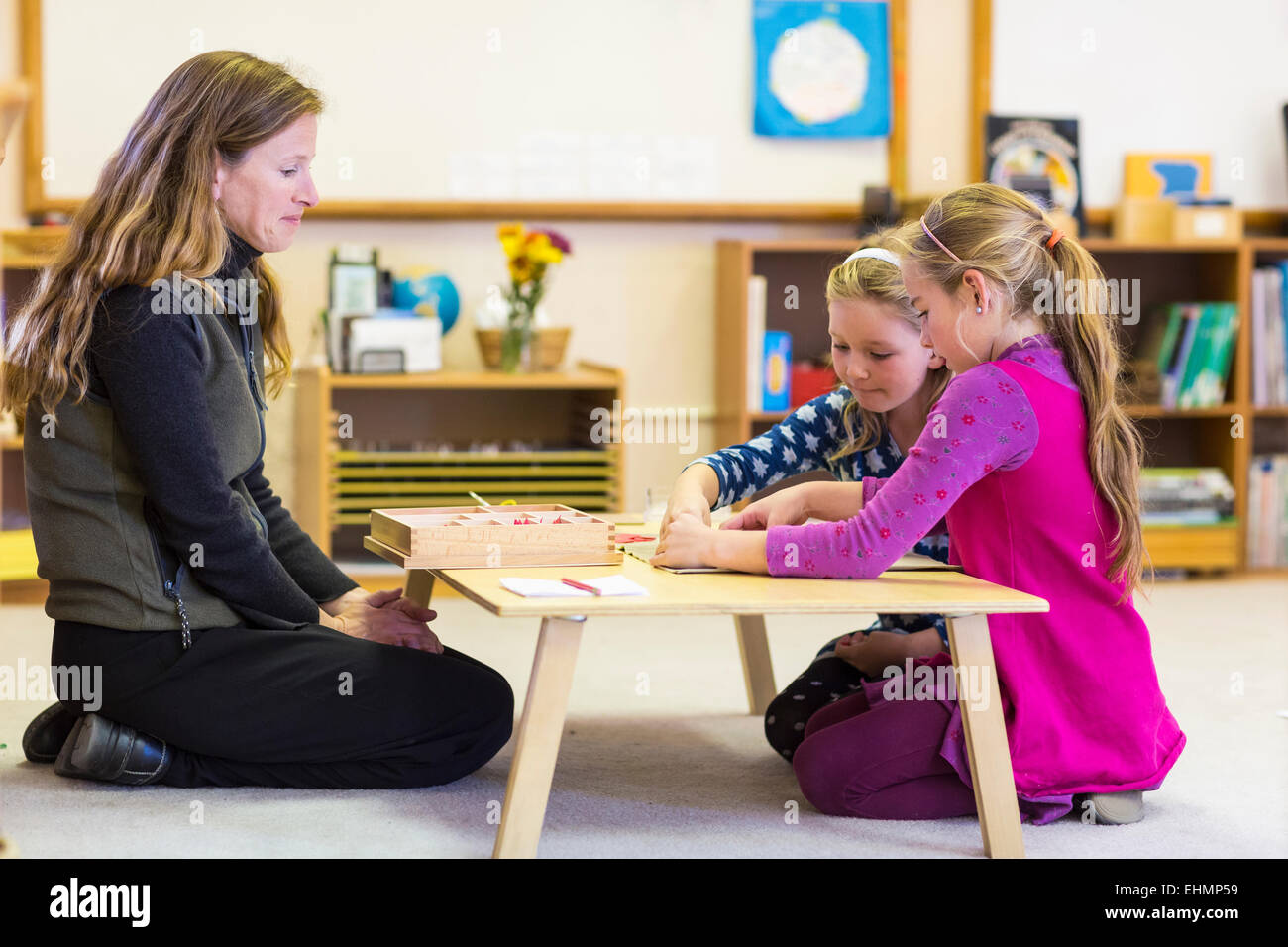 Montessori teacher helping students in classroom Stock Photo - Alamy
