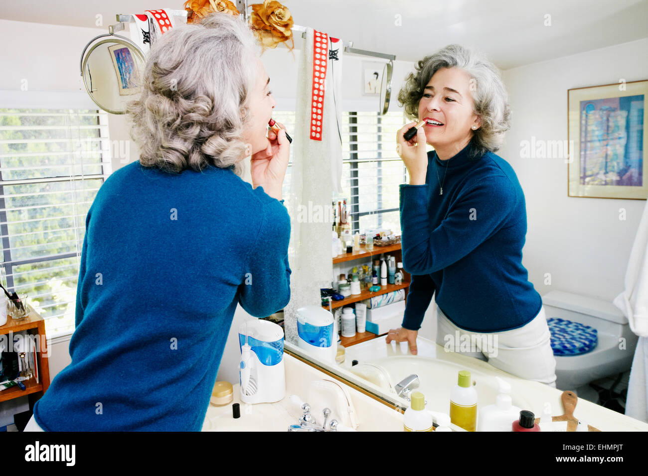 Caucasian woman applying makeup in mirror Stock Photo - Alamy