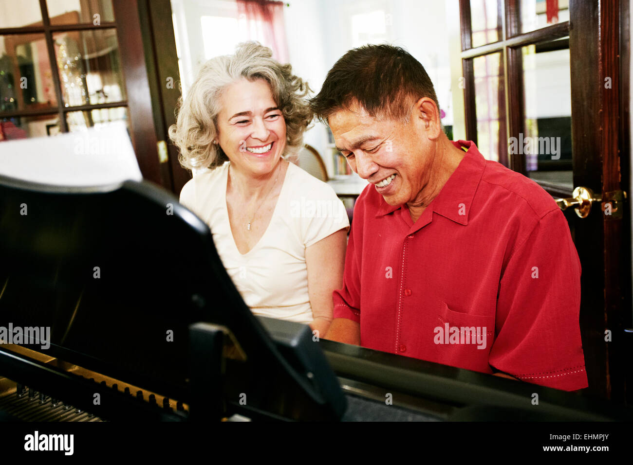 Couple playing piano together in living room Stock Photo - Alamy