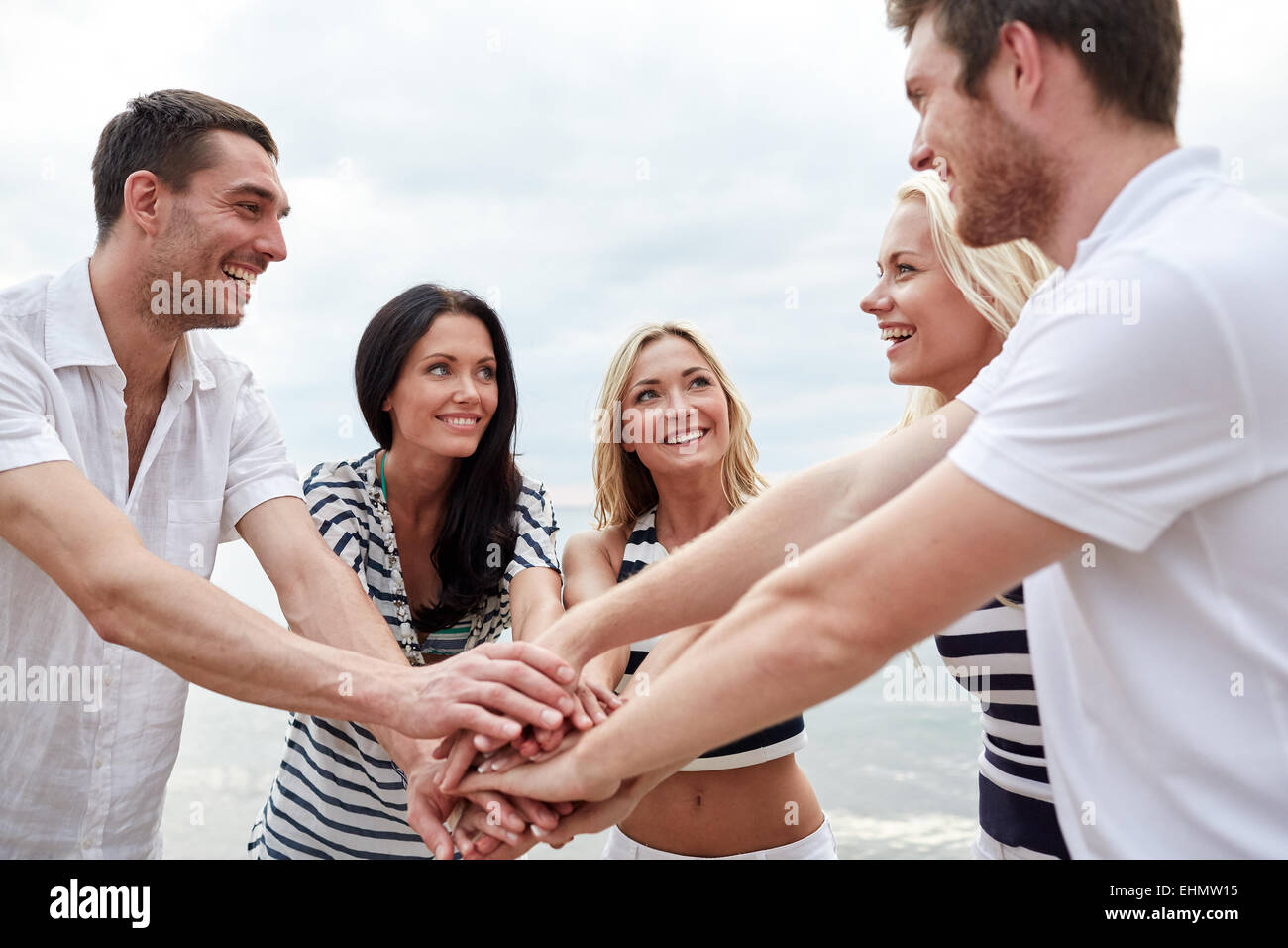 smiling friends putting hands on top of each other Stock Photo - Alamy