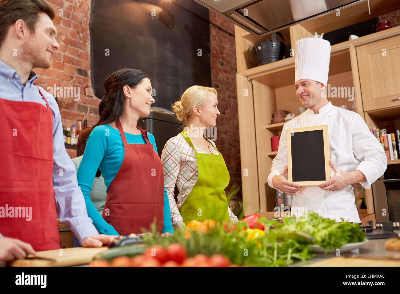 happy friends and chef cook with menu in kitchen Stock Photo - Alamy