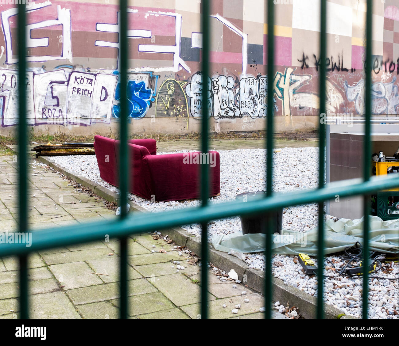 View through fence of vacant stand with discarded sofa and graffiti ...
